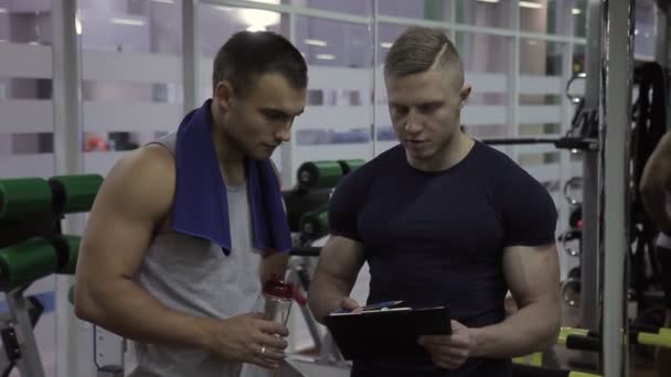 Sportsman is doing barbell biceps curl and his male trainer is ...