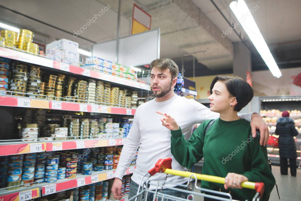 Una pareja joven camina a través de un supermercado con un carrito de ... Una pareja joven camina a través de un supermercado con un carrito de ...