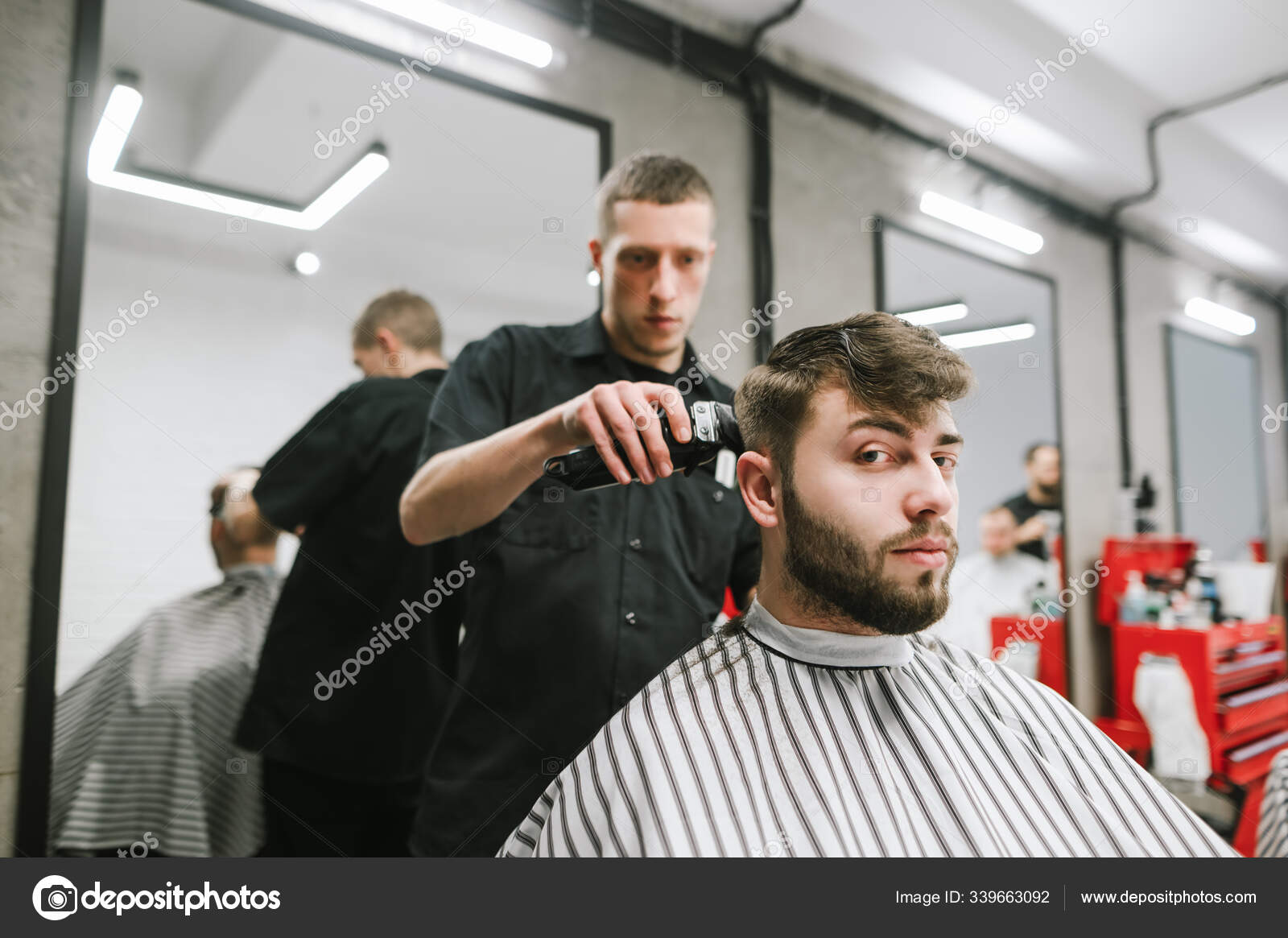Portrait of a bearded man clipping in a barbershop and looking intently ...
