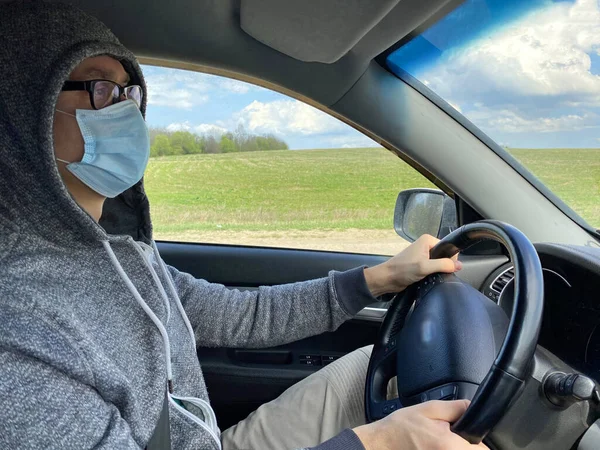 Man in medical protective mask driving car, close-up. Hygienic mask to ...