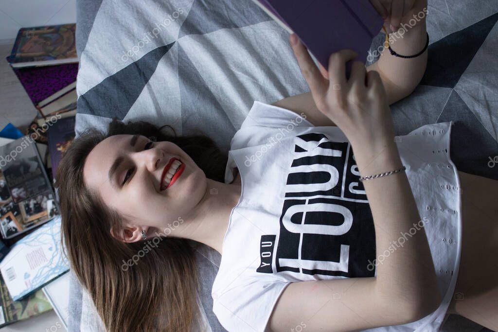 chica leyendo un libro acostado en la cama con un montón de libros ...