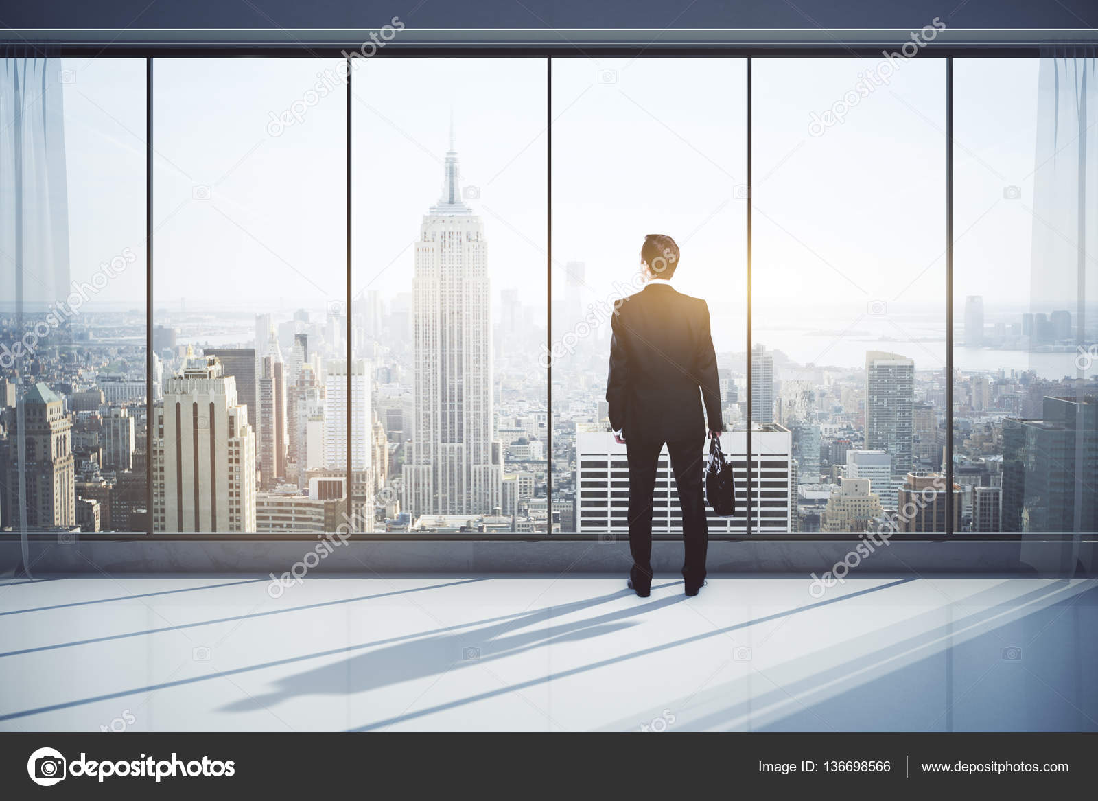 Back view of man with briefcase in modern interior with city view ...
