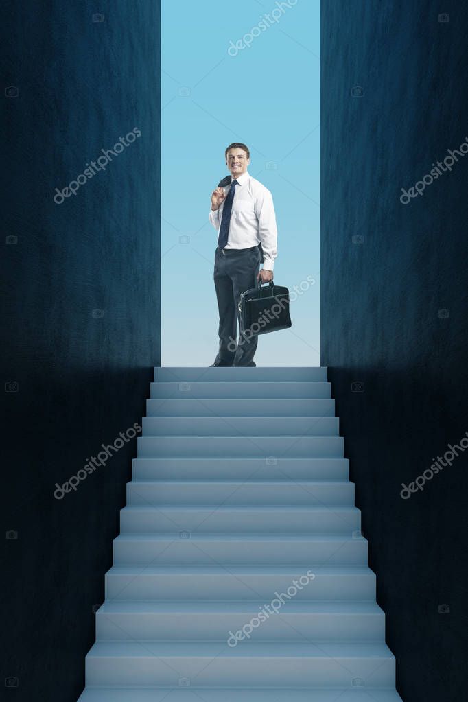 Empresario de pie en la parte superior de la escalera de hormigón con vista al cielo y paredes ...