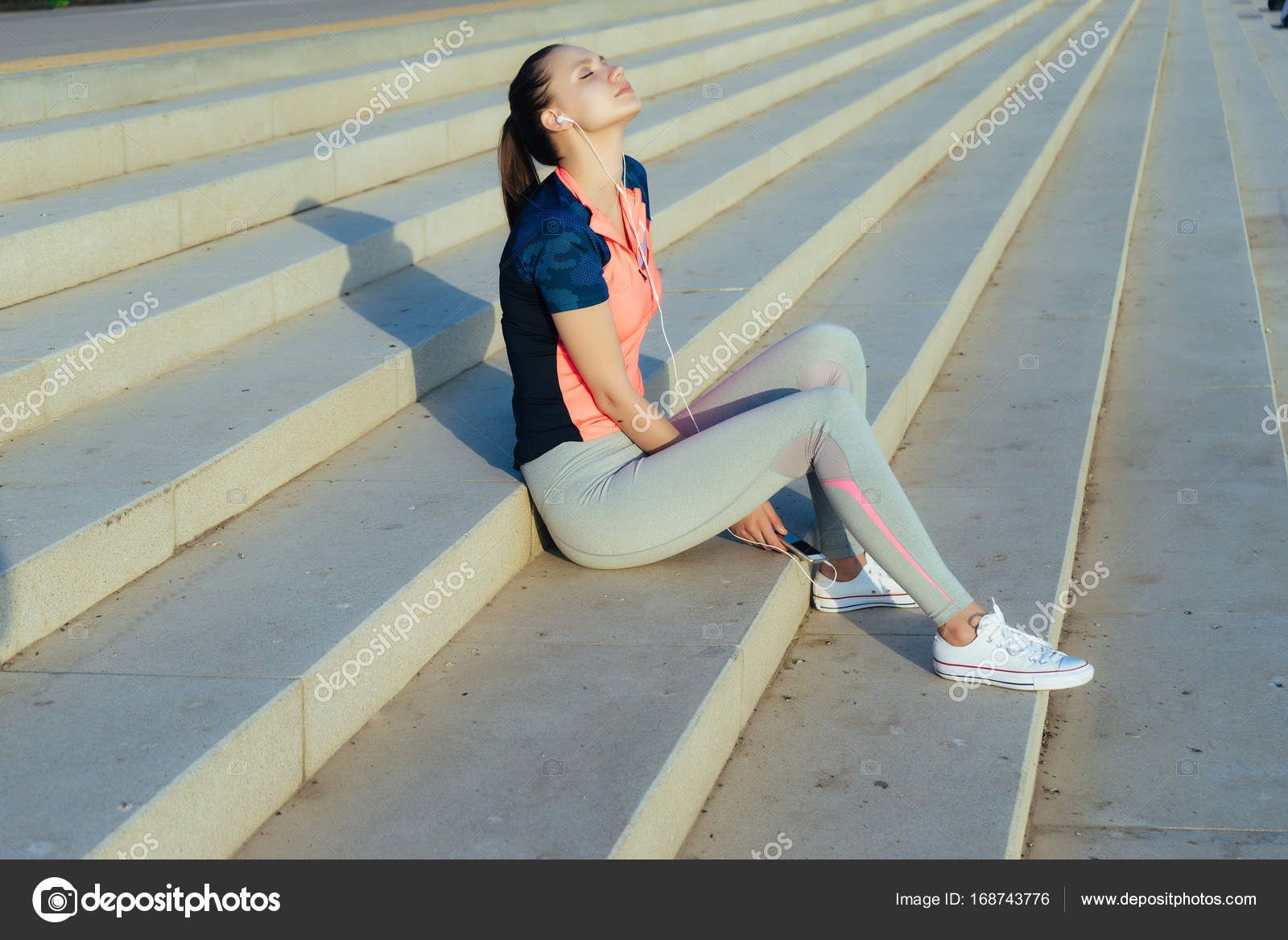 Girl with a phone in hands on headphones resting on the steps — Stock ...