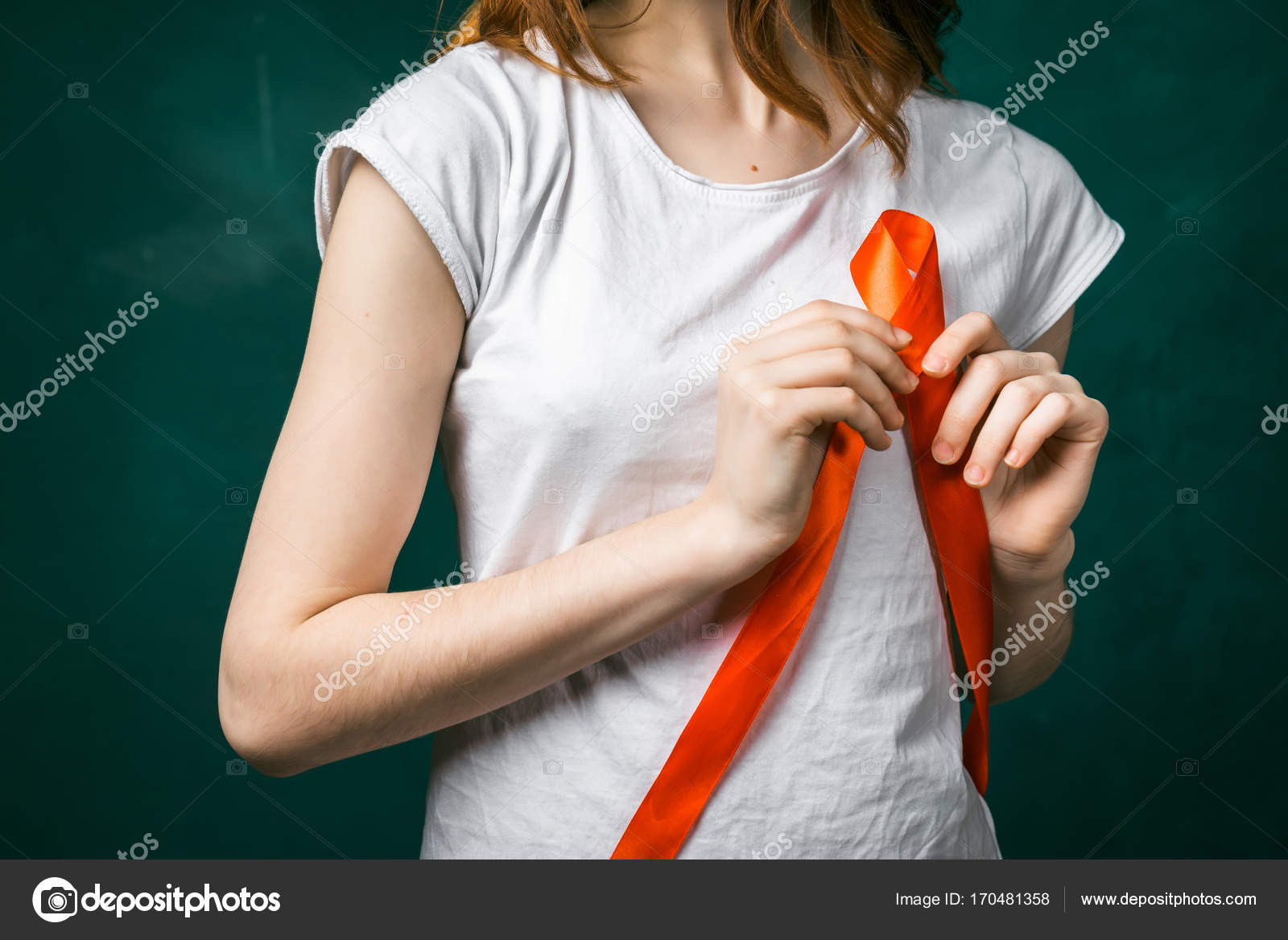 A girl in a white T-shirt fastens a red satin ribbon which is a symbol ...