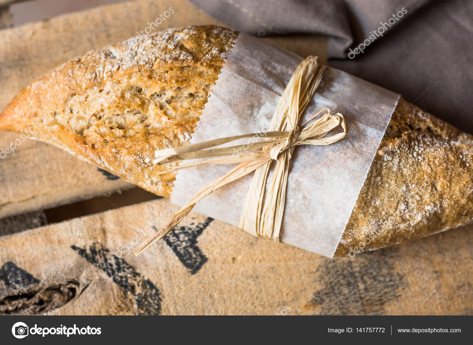 Rye whole wheat bread roll with golden crust wrapped in parchment paper ...