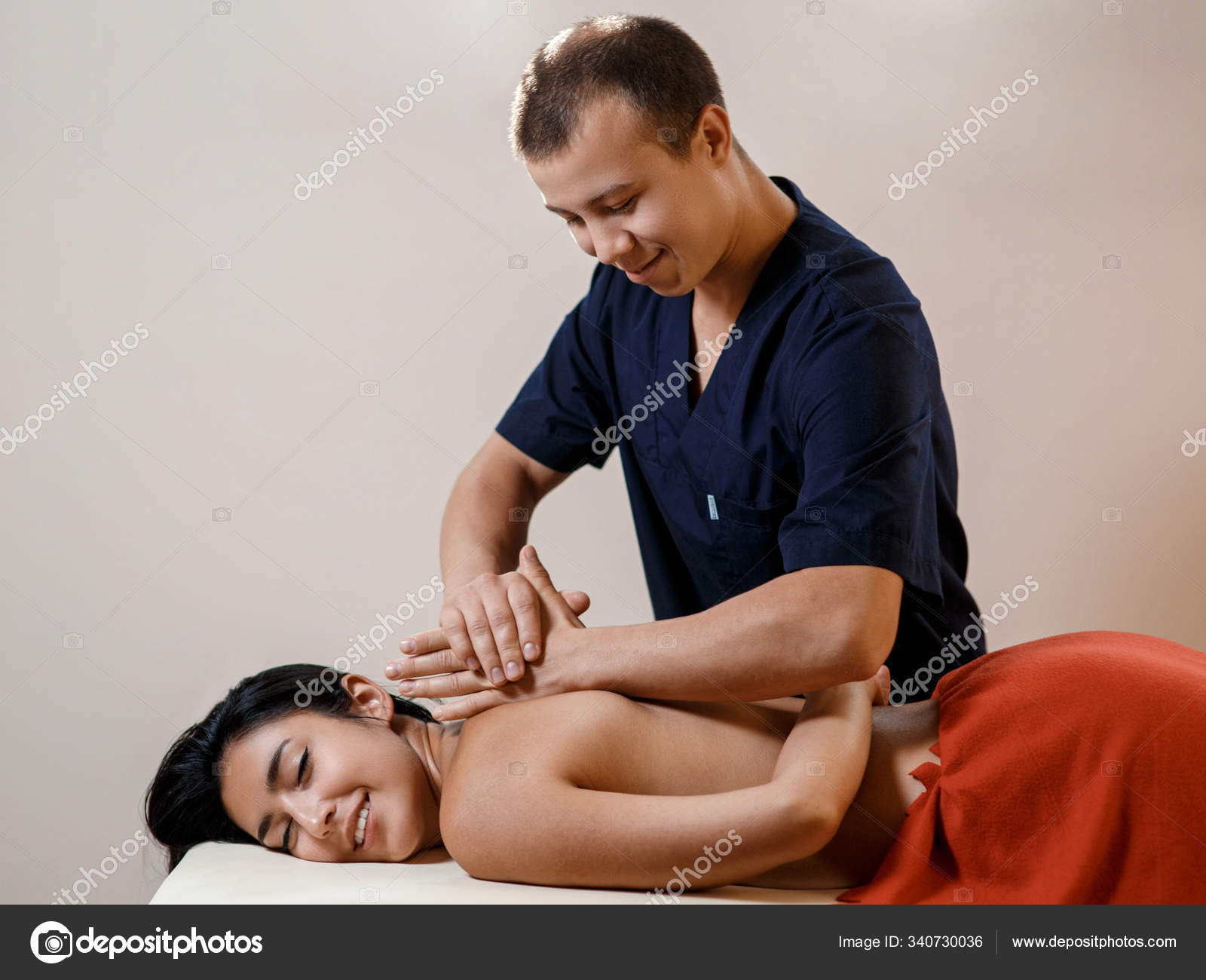 A young woman gets a massage procedure. Masseur makes back massage ...