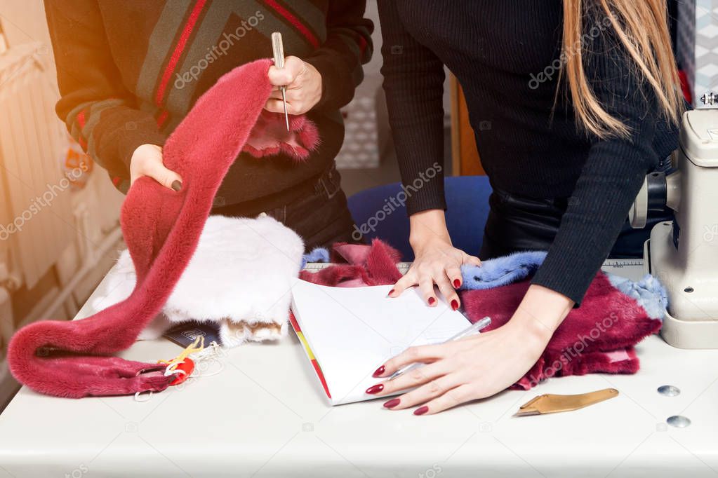 Clode up of a two young women furriers are talking how to properly cut ...