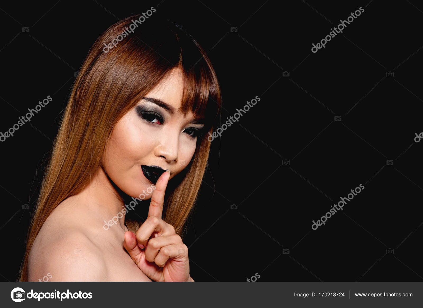 Gothic young Asian woman with secret hush pose isolated on black ...