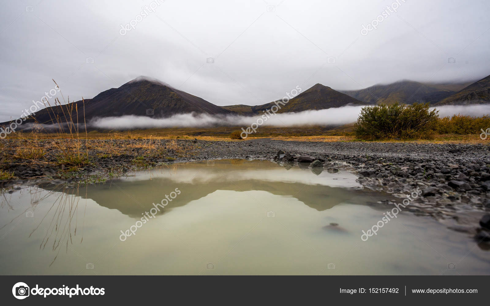 Puddle of rain with reflection in the front. Mountain with fog i Stock ...