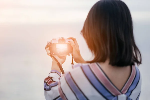 young women standing alone hold camera take photo with sea backg ...
