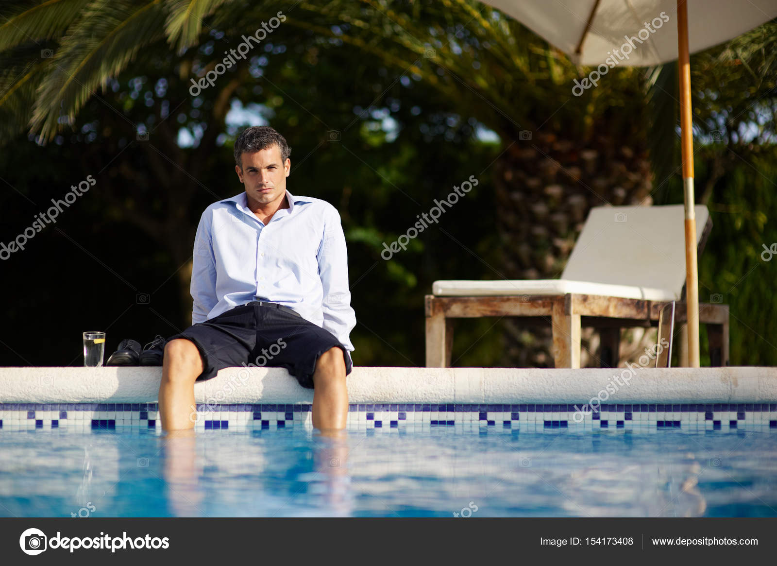 Man sitting near swimming pool Stock Photo by ©ImageSource 154173408