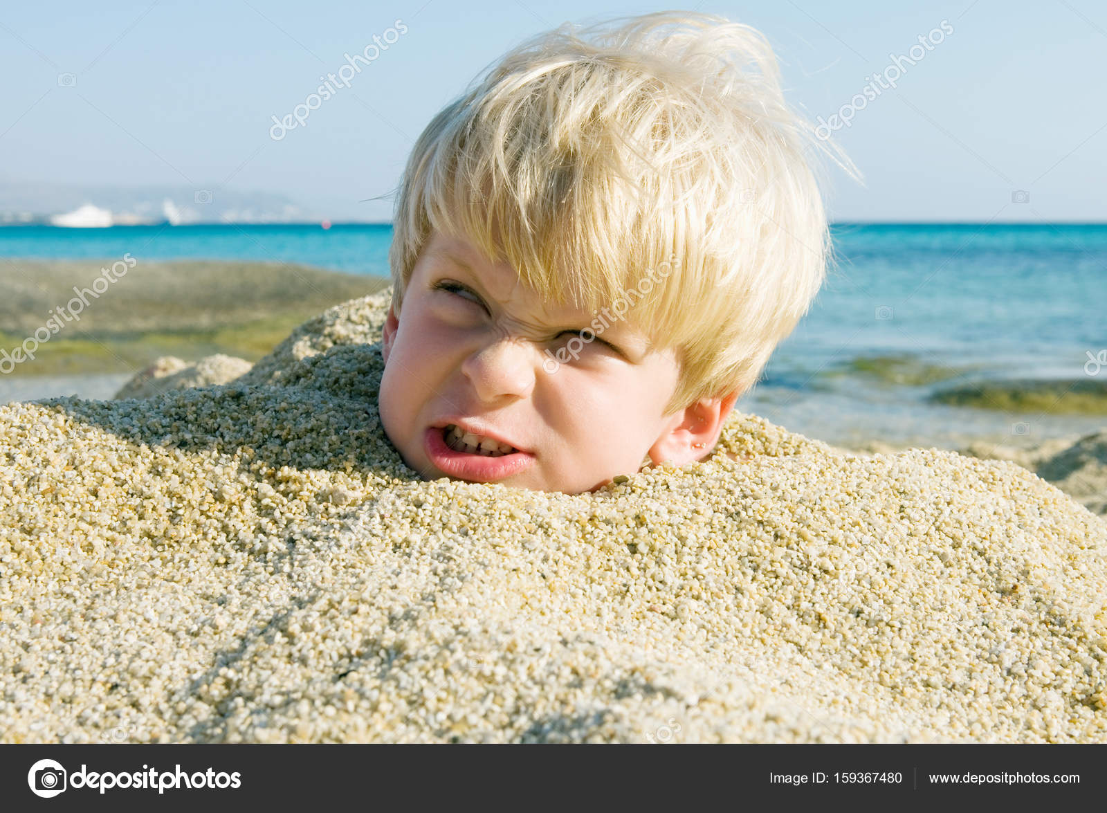 Scowling boy buried in sand — Stock Photo © ImageSource #159367480