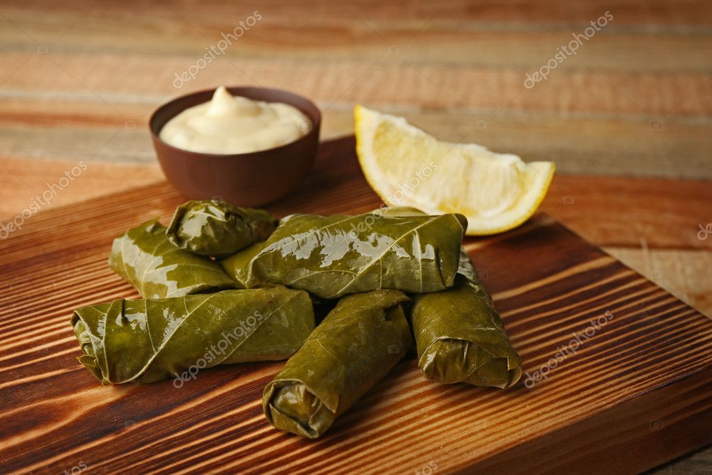 Stuffed delicious Dolma with sauce and lemon on wooden board Stock ...