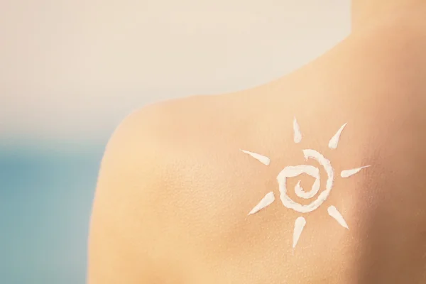 Woman with sunscreen in sun shape on shoulder. Skin care concept ...