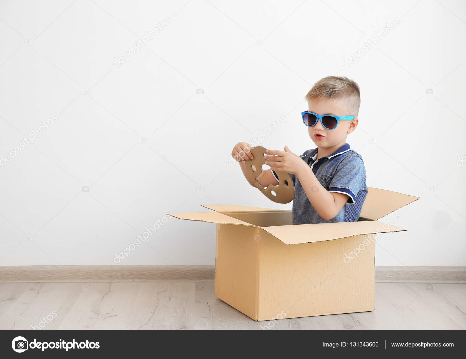 Boy playing with cardboard box Stock Photo by ©belchonock 131343600