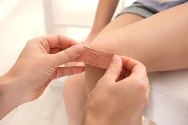 Woman applying sticking plaster Stock Photo by ©belchonock 133703592