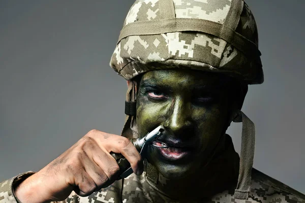 Portrait of soldier with painted face on grey background, close up view ...