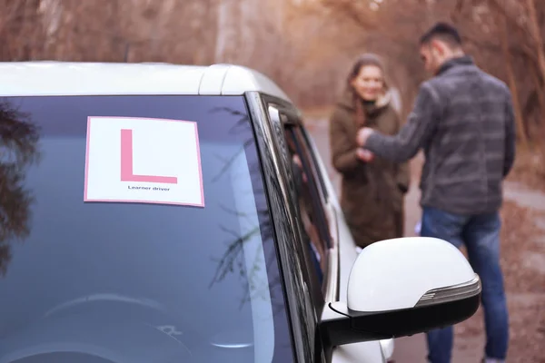 Learner driver sign on car windscreen. Blurred view of instructor and ...