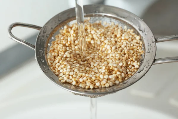 Washing quinoa seeds in sieve — Stock Photo © belchonock #147579285