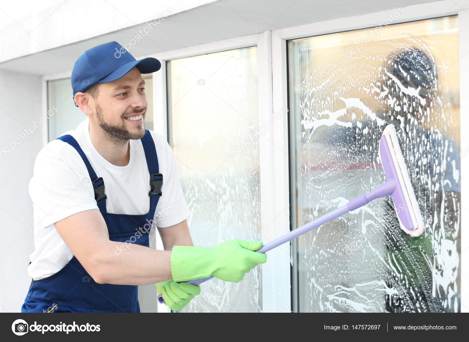 Young man washing window Stock Photo by ©belchonock 147572697