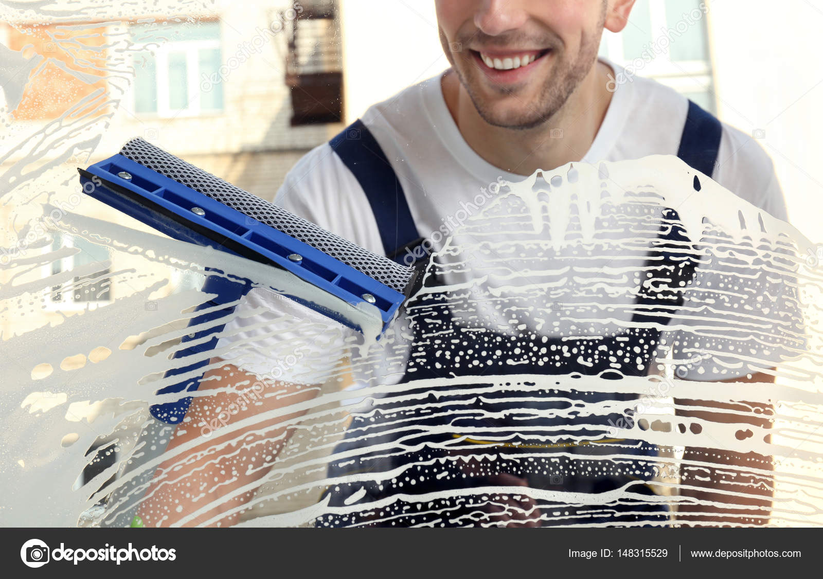Young man washing window Stock Photo by ©belchonock 148315529