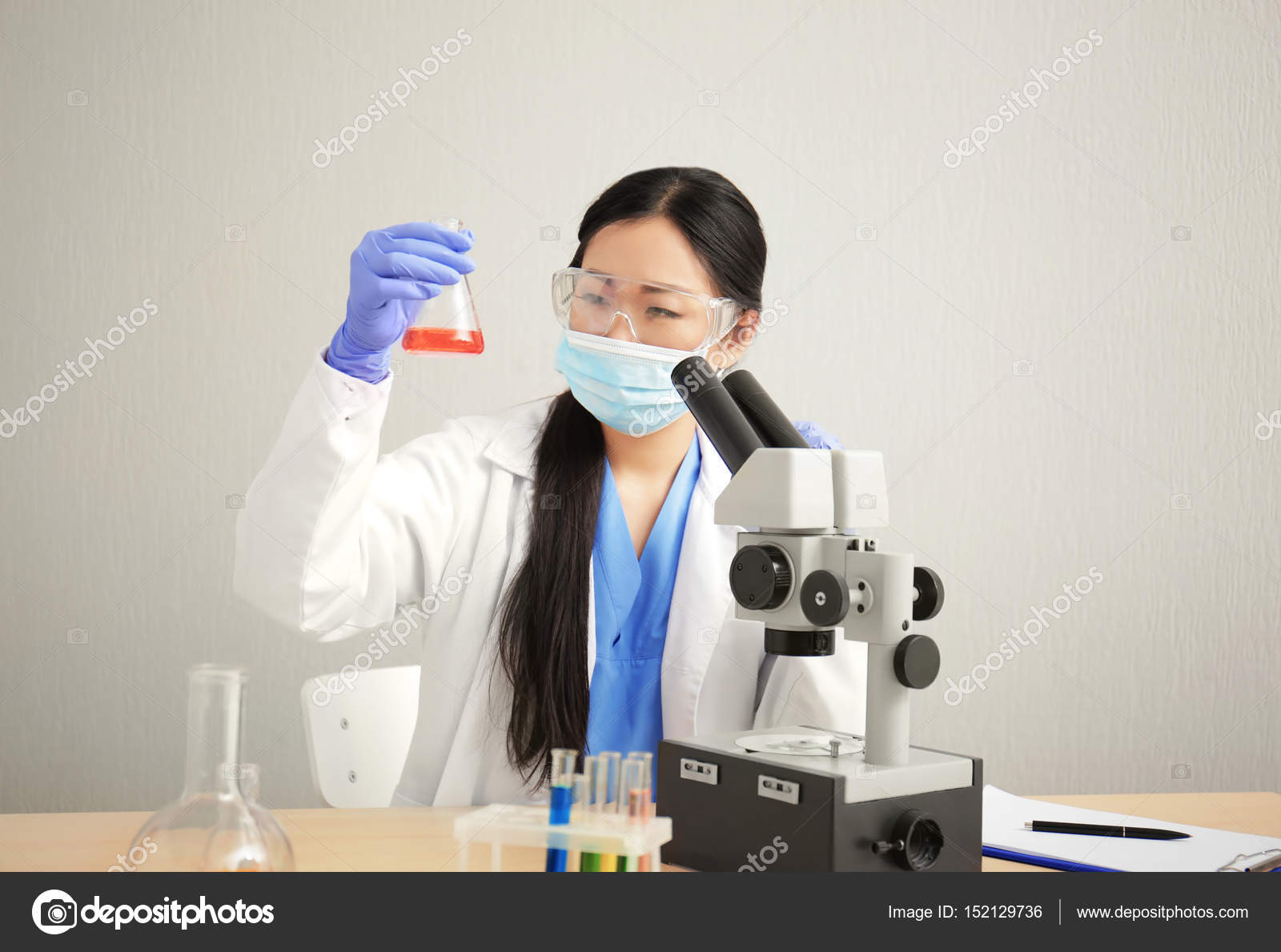 Young doctor working with microscope at table on light background Stock ...