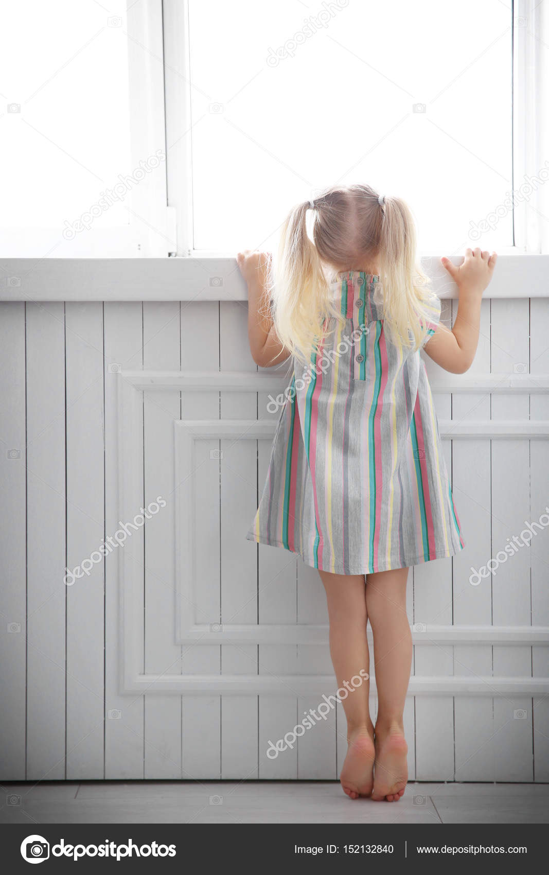 Girl standing near window Stock Photo by ©belchonock 152132840
