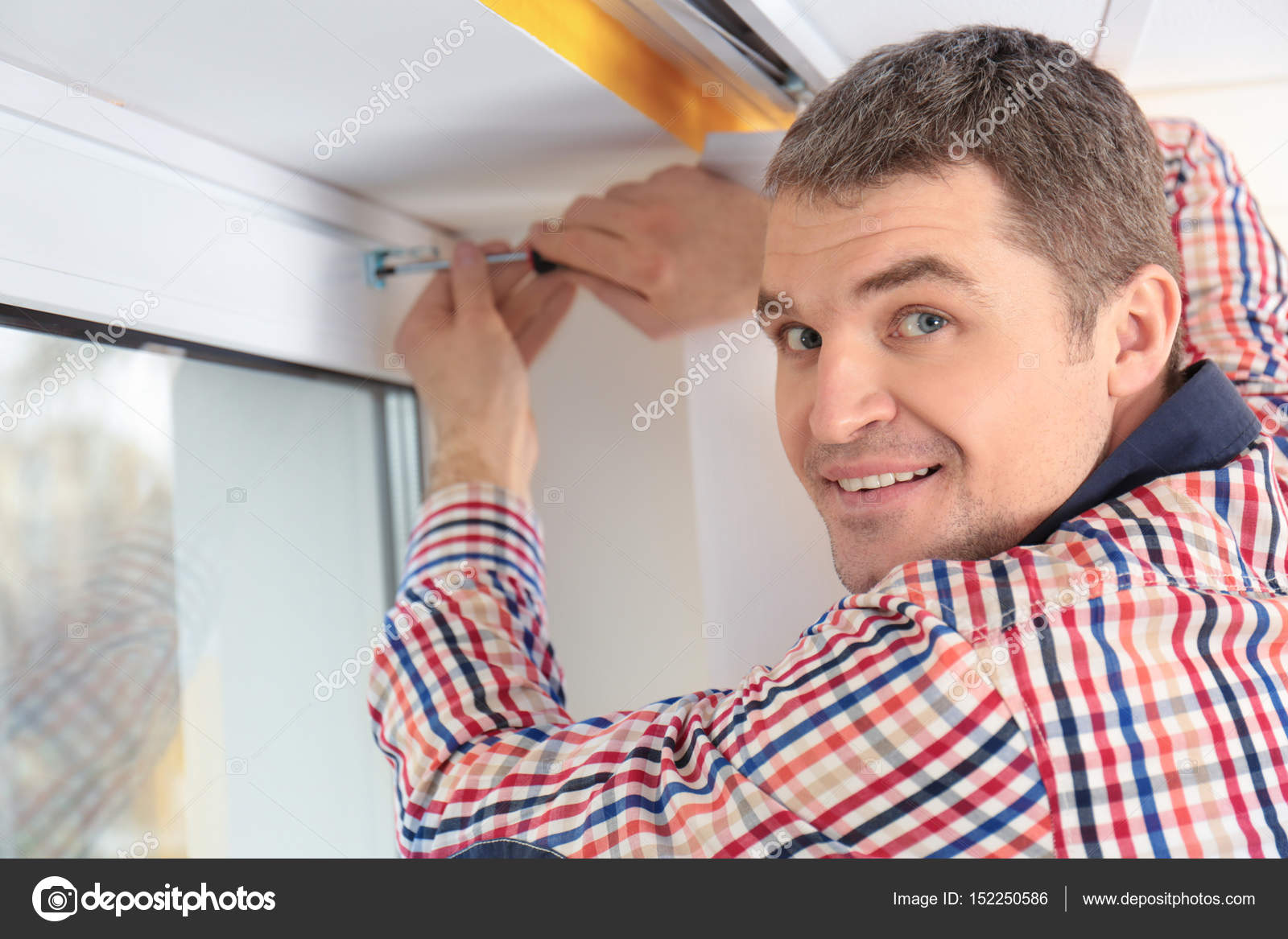 Young man installing window Stock Photo by ©belchonock 152250586