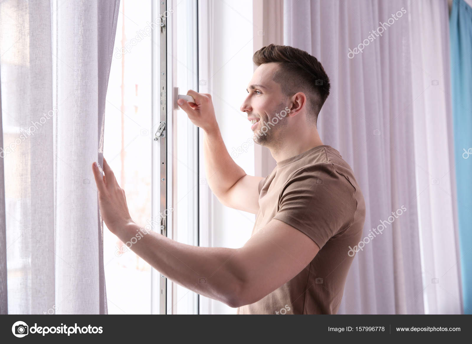 Smiling man opening window Stock Photo by ©belchonock 157996778