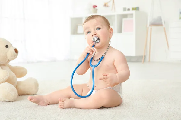Cute little baby with stethoscope and toy bear playing at home. Health ...