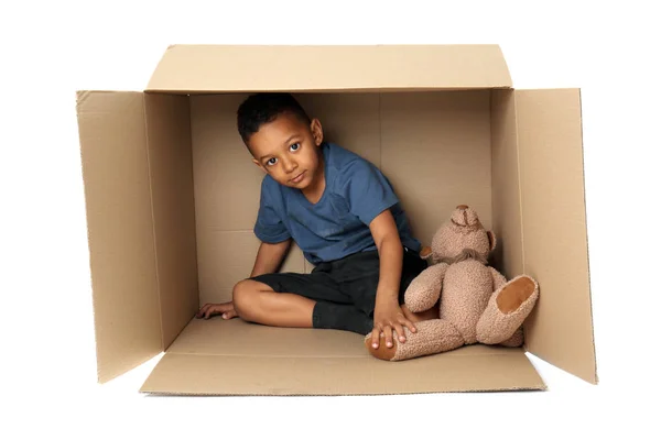Cute little boy living in box on white background. Poverty concept ...
