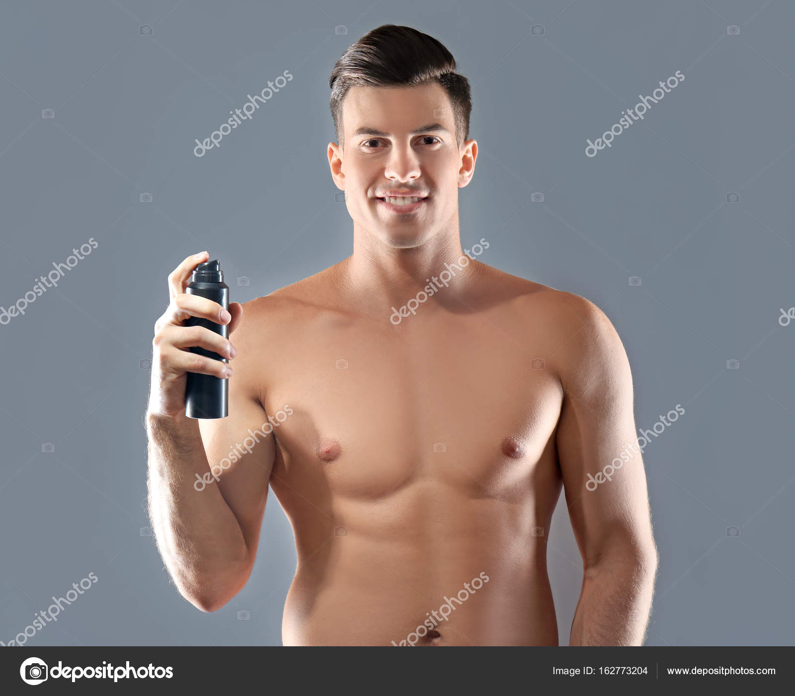 Handsome young man with deodorant on grey background — Stock Photo ...