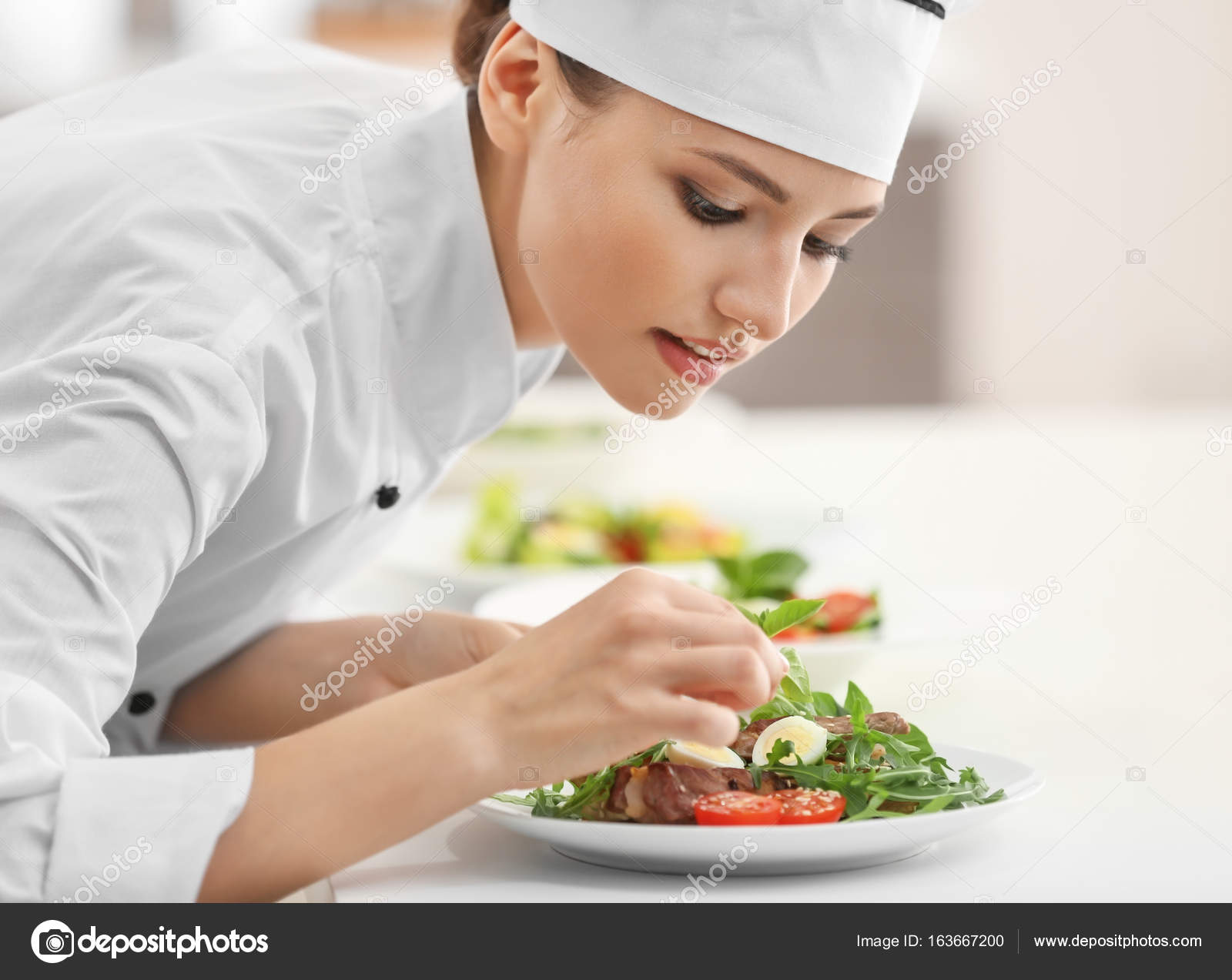 Young female chef cooking in kitchen Stock Photo by ©belchonock 163667200