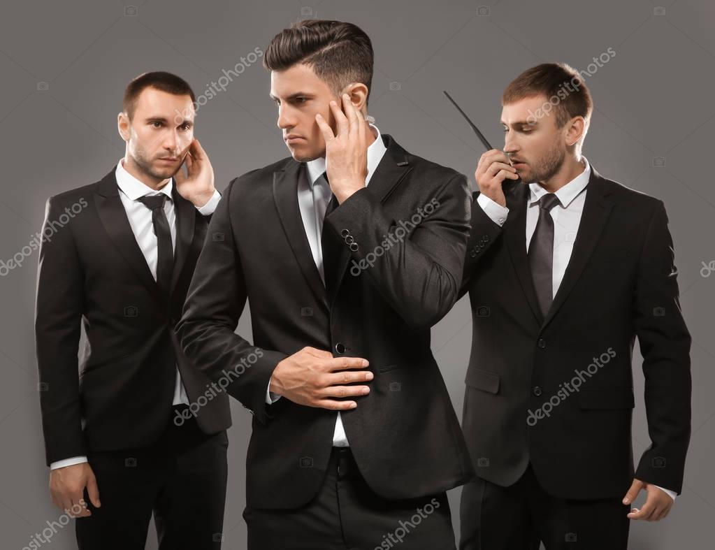 Handsome bodyguards on grey background — Stock Photo © belchonock ...