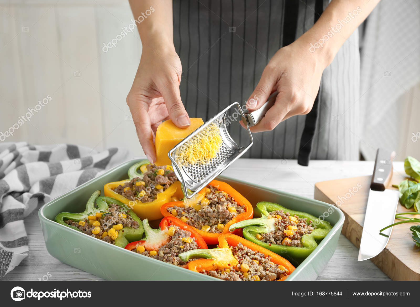 Woman adding cheese to quinoa stuffed peppers Stock Photo by ...