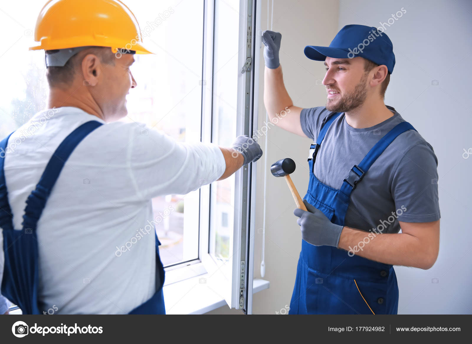 Construction worker with trainee installing window in house Stock Photo ...