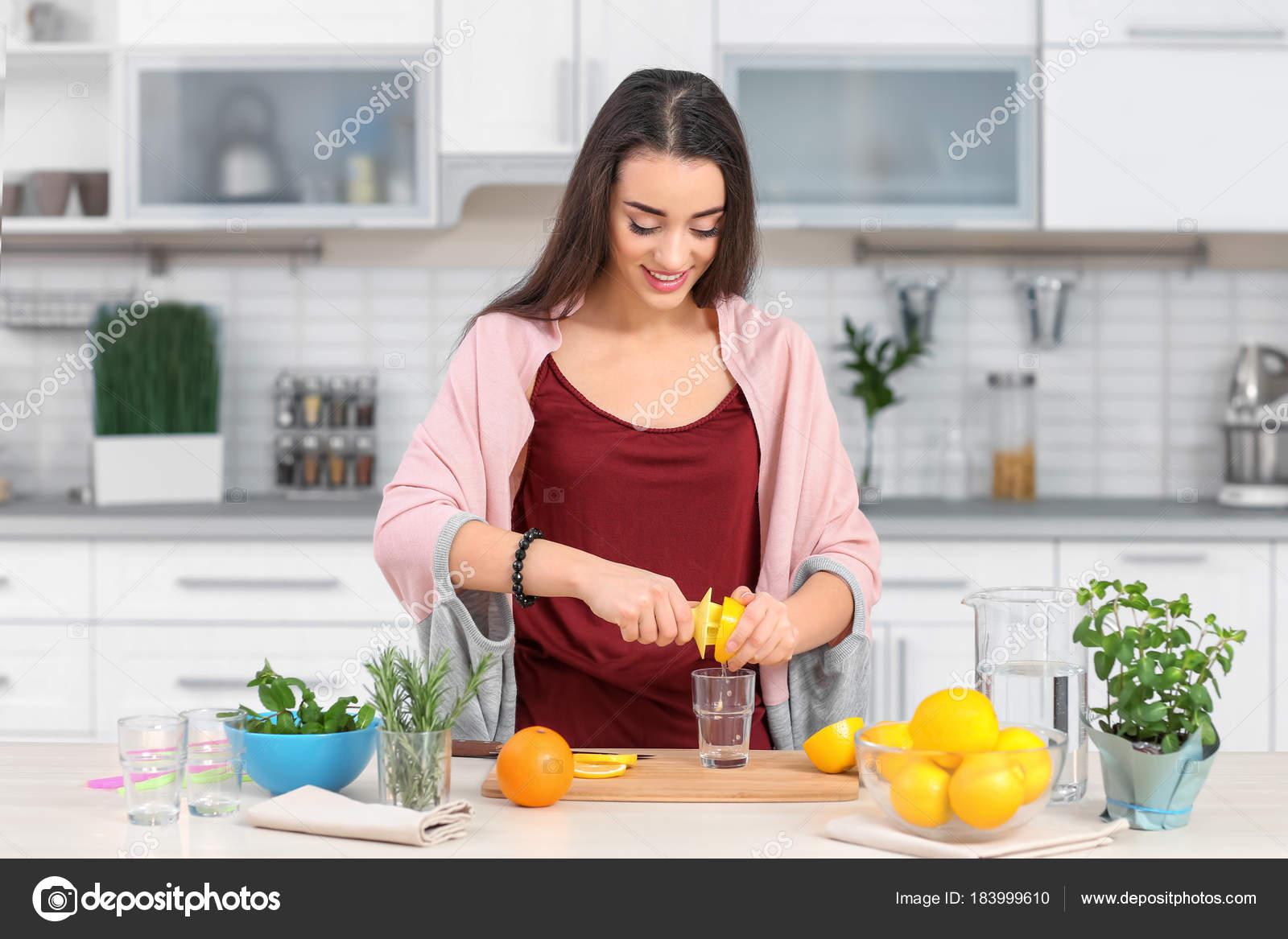 Young woman preparing lemonade Stock Photo by ©belchonock 183999610