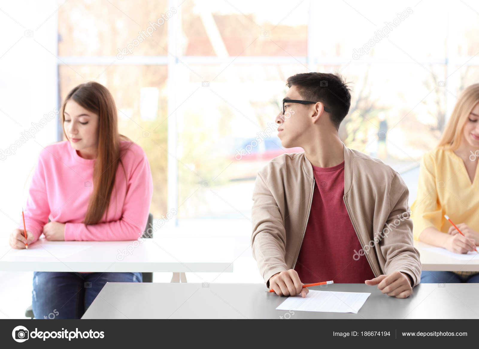 Asian student trying to copy answers of classmate at exam Stock Photo ...