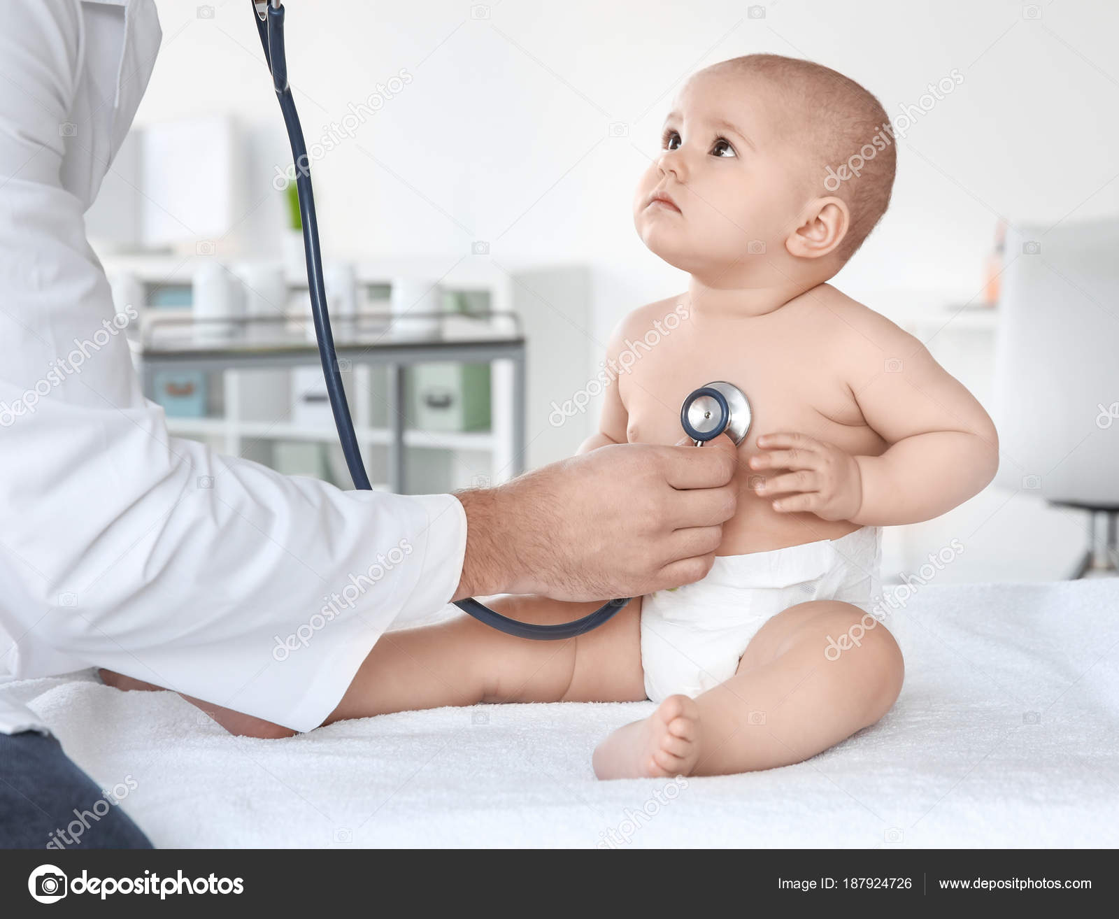 Doctor examining cute baby in clinic Stock Photo by ©belchonock 187924726