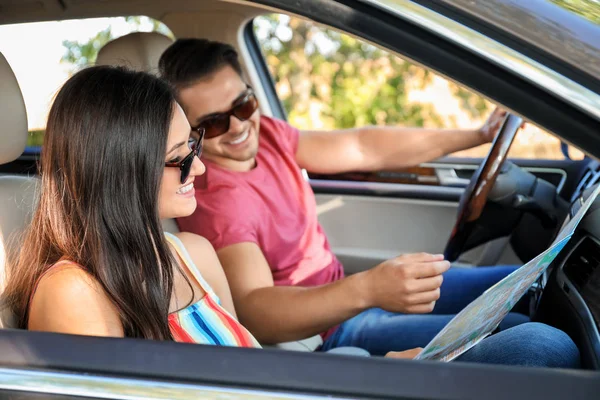 Beautiful young couple with map in car - Stock Image - Everypixel