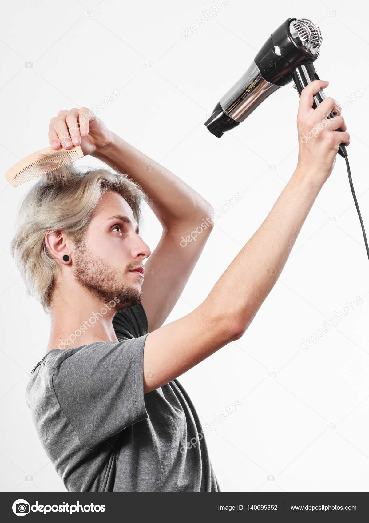 Young man drying hair with hairdryer — Stock Photo © Anetlanda #140695852