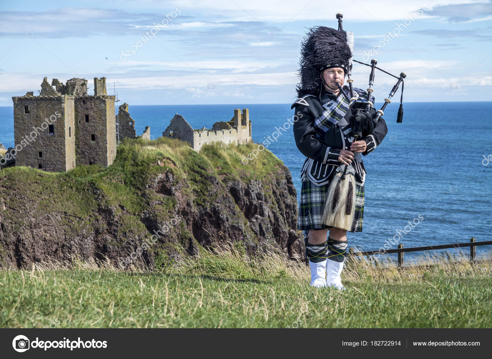 Traditional scottish bagpiper in full dress code at Dunnottar Castle in ...