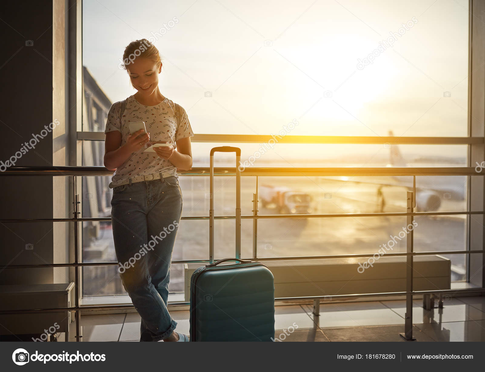 Young woman waiting for flying at airport at window with suitcas ...