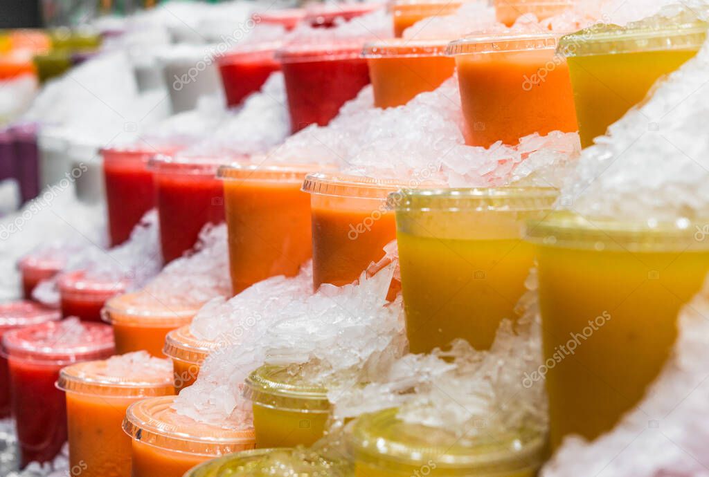 Una variedad de diferentes batidos de frutas de colores en el puesto de ...