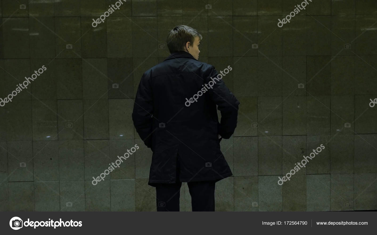 Lonely young man from behind at subway station. Young man waits for a ...