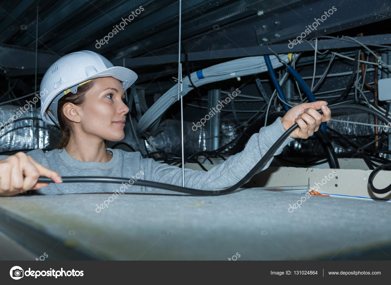 Female contractor passing cables through roof space Stock Photo by ...