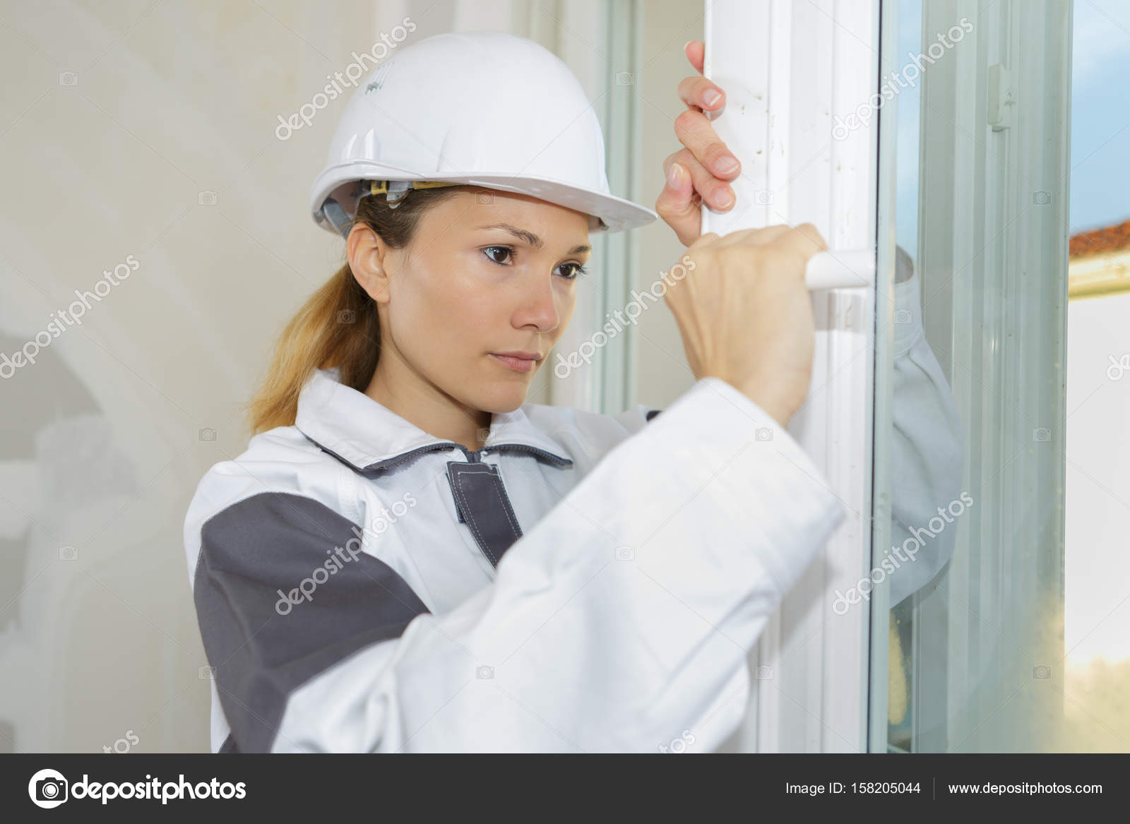 Female construction worker installing window in house Stock Photo by ...