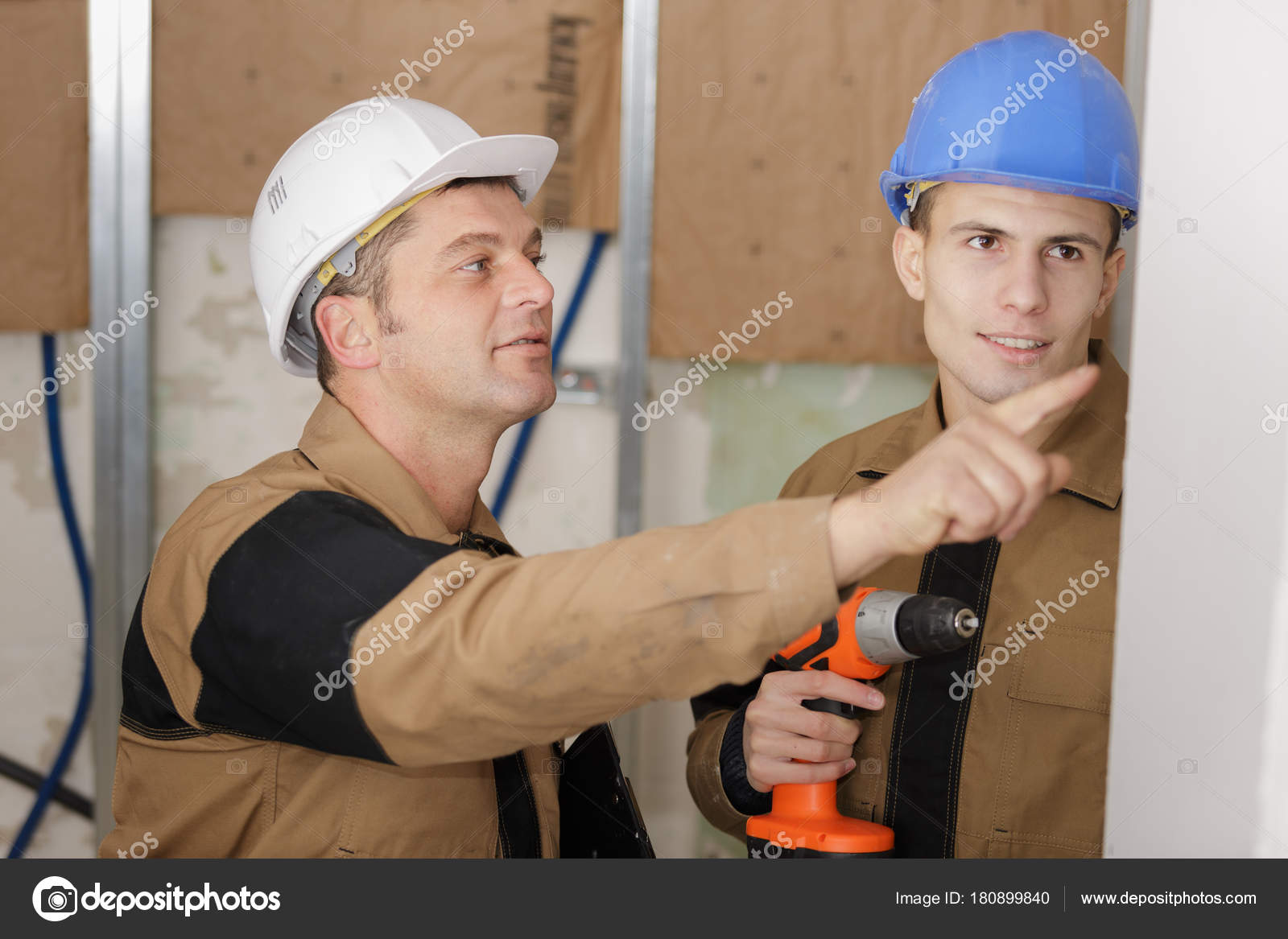 Craftsman watching over his apprentice drill a wall Stock Photo by ...