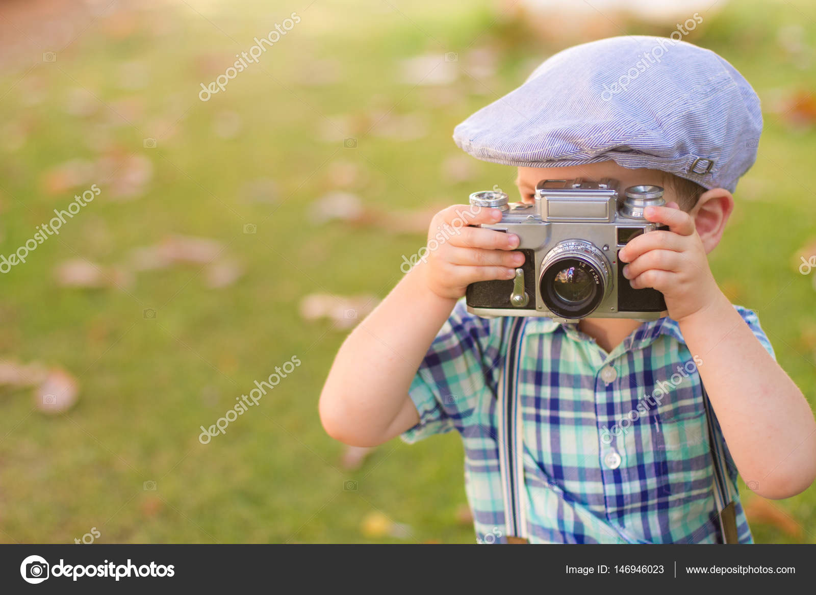 Little boy with an old camera shooting outdoor. using a vintage retro ...